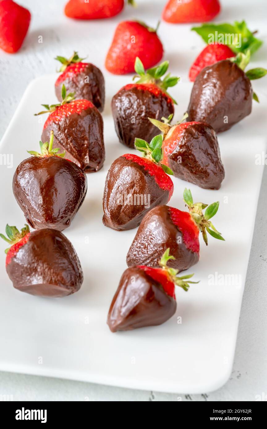 Chocolate-dipped strawberries on the white serving plate Stock Photo ...