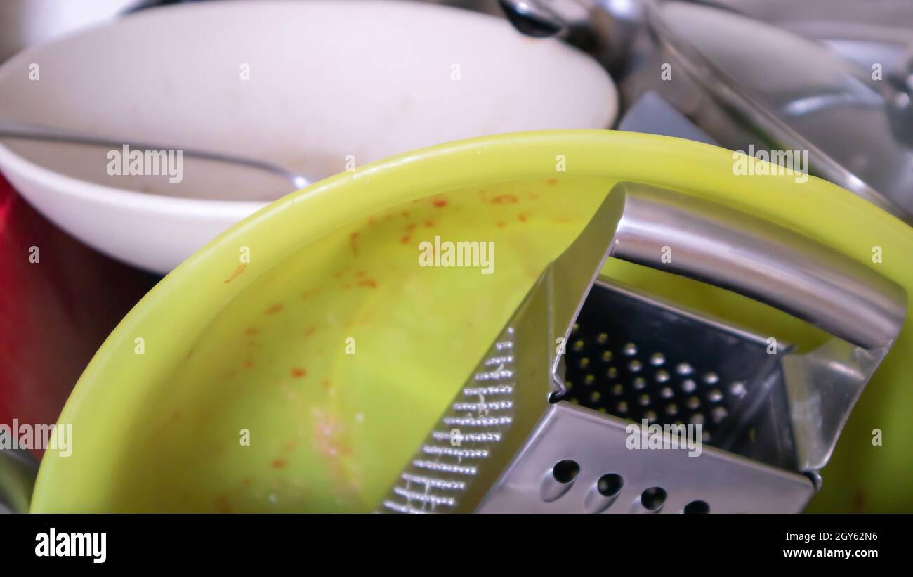 The kitchen utensils in the wash basin need to be washed. A pile of ...