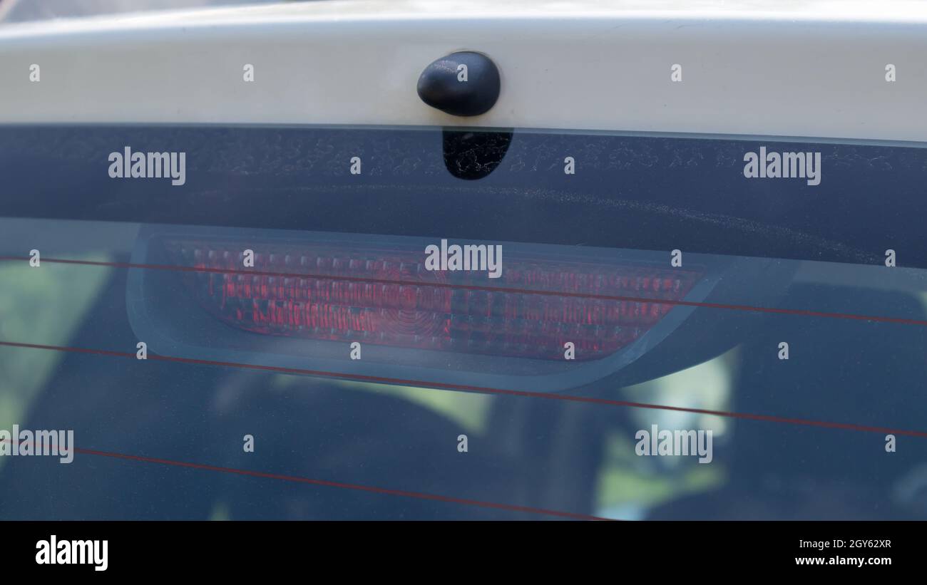 Rear window of a dusty white car with a stoplight behind glass, close ...