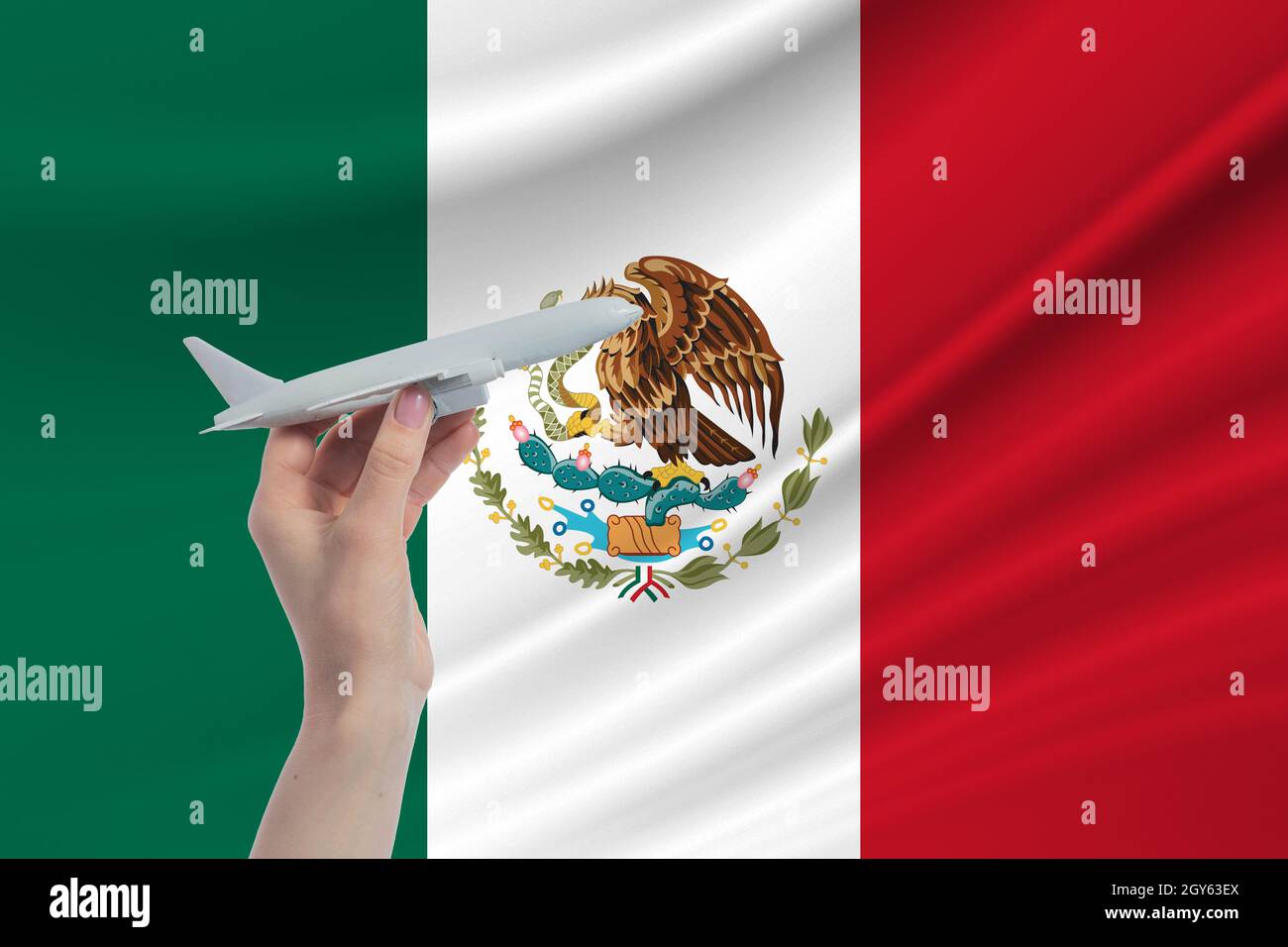 Airplane in hand with national flag of Mexico. Travel to Mexico Stock ...