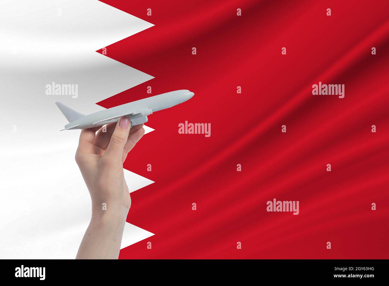 Airplane in hand with national flag of Bahrain. Travel to Bahrain Stock ...