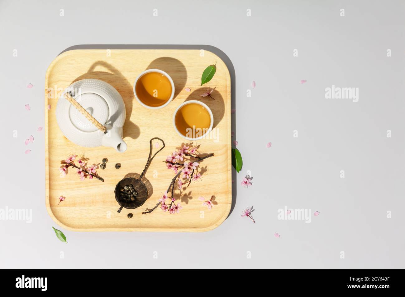 Tea concept, two white cups of tea, teapot, tea strainer and spring ...