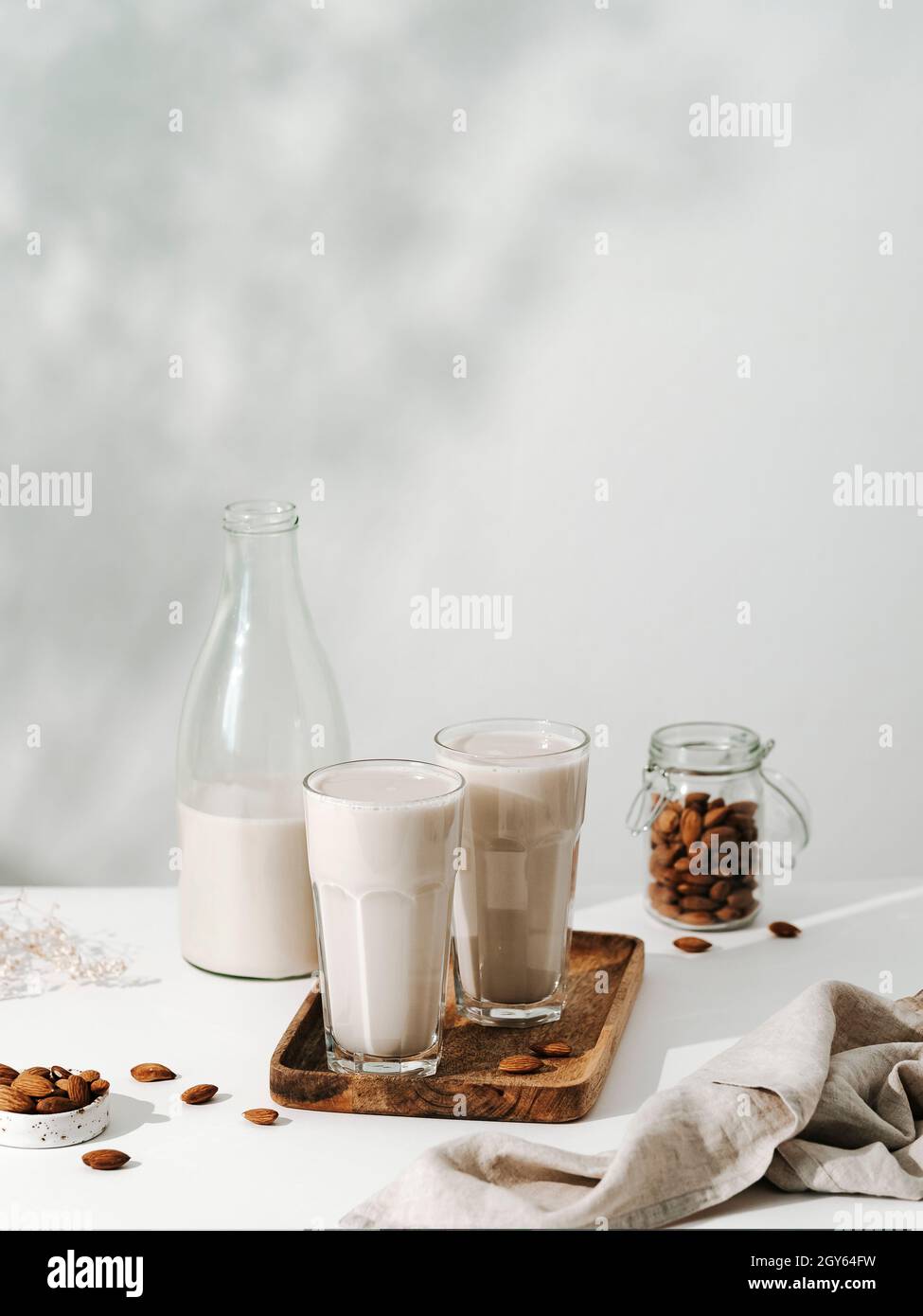 Almond vegan milk on the table, copy space. Vertical. Modern light ...