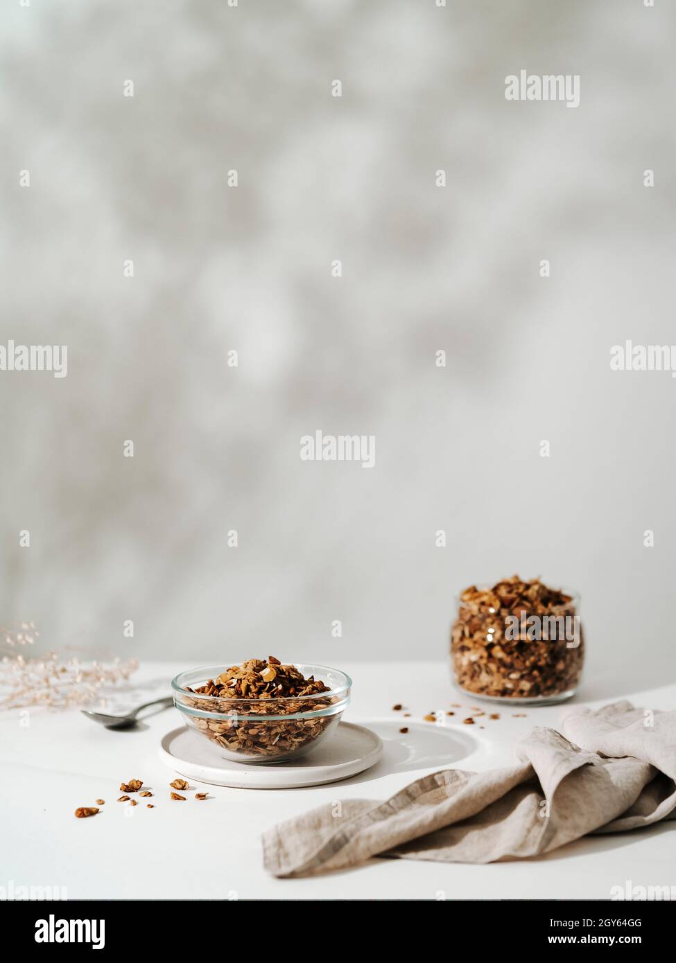Gluten-free granola in glass bowl on the table with floral shadows on ...