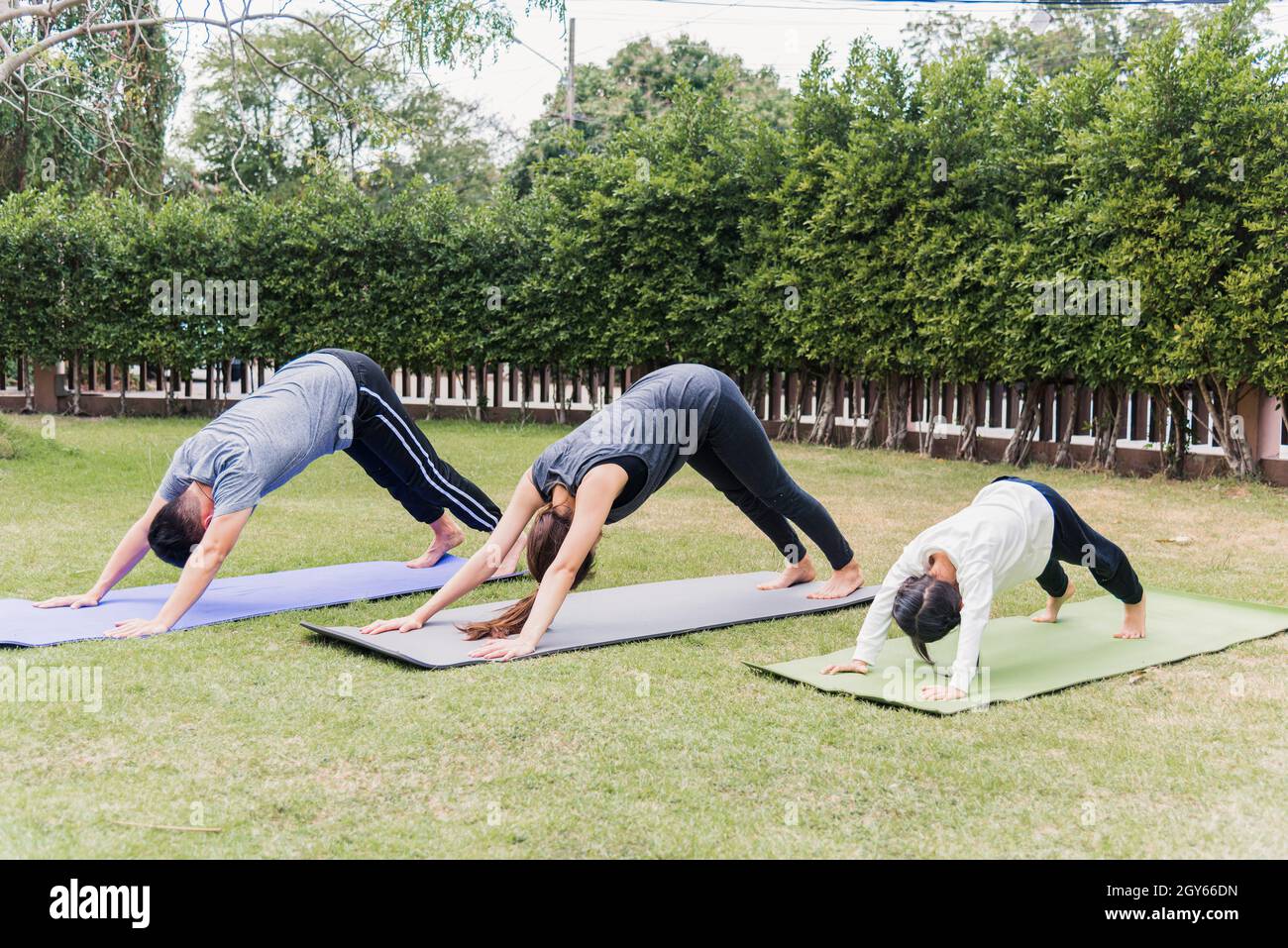 Asian young mother, father practicing doing yoga exercises with child ...