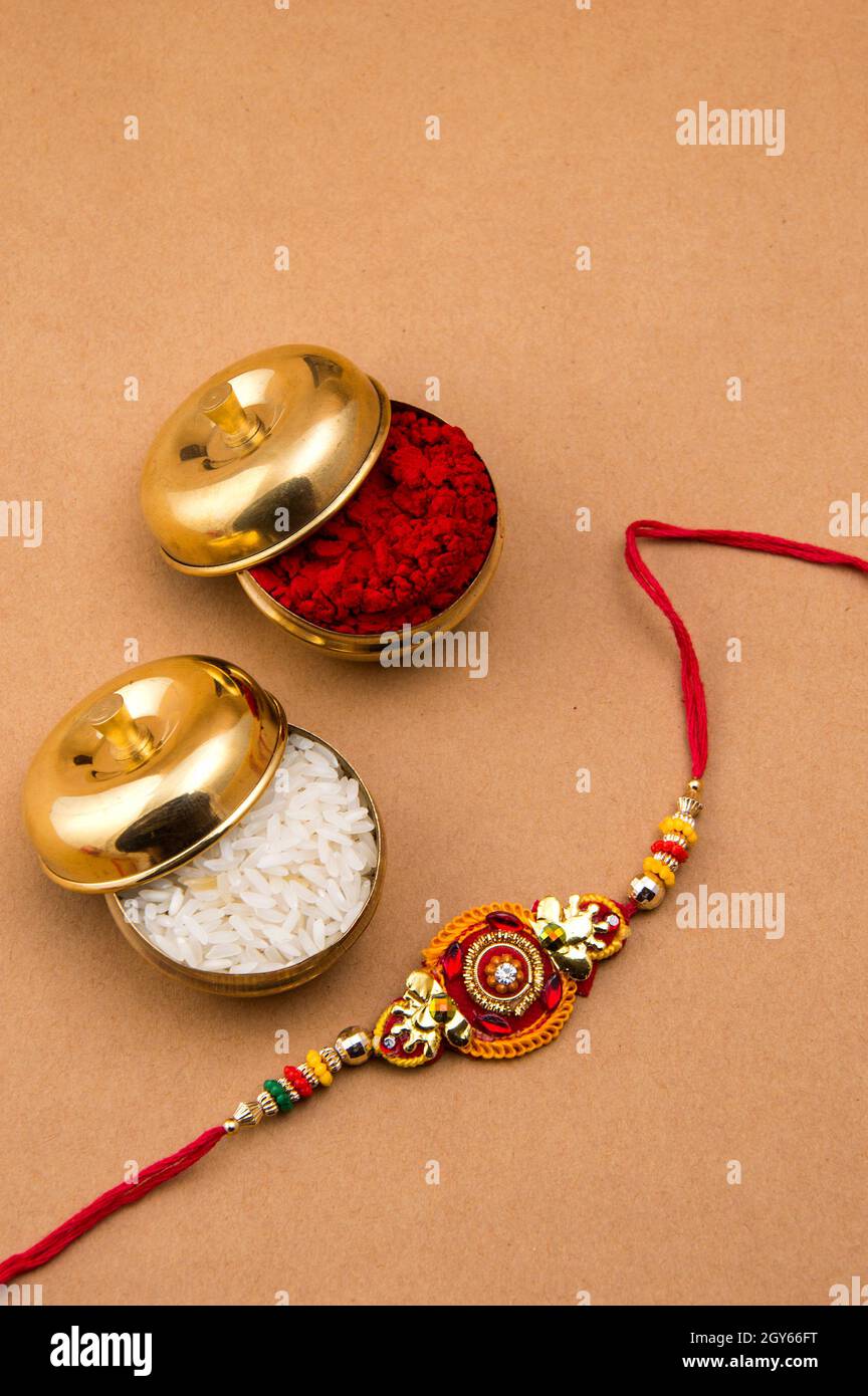 Raksha Bandhan background with an elegant Rakhi, Rice Grains and Kumkum ...