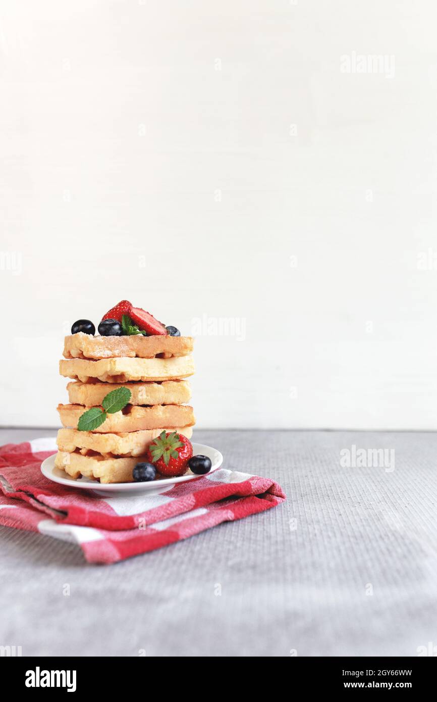 Stack of waffles on a white plate on the towel and table with blueberry ...
