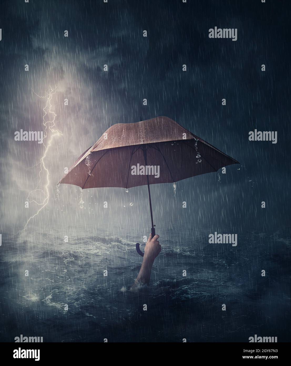 Human hand holding an umbrella sinking in the ocean. Surreal and ...