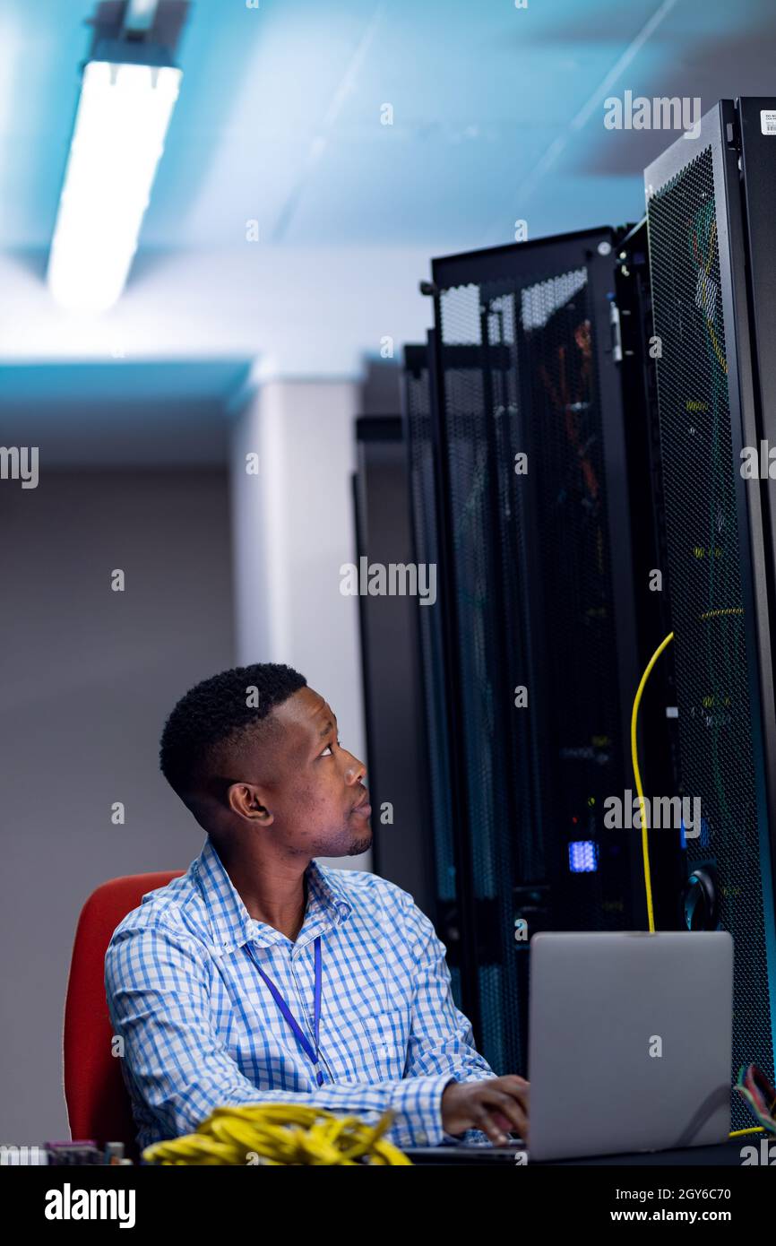 Smiling african american male computer technician using laptop working ...