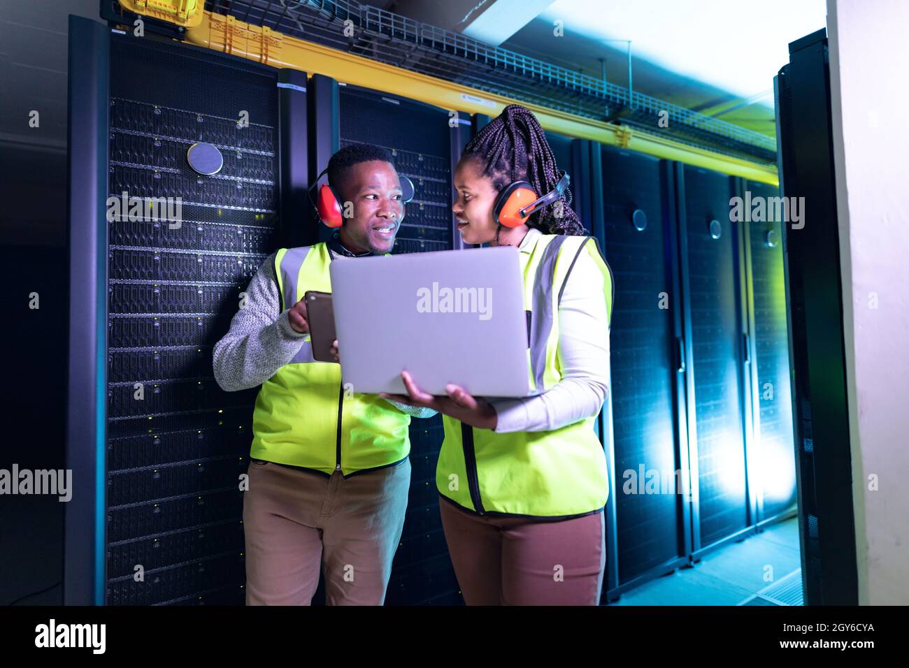 African american computer technicians wearing headphones using laptop ...