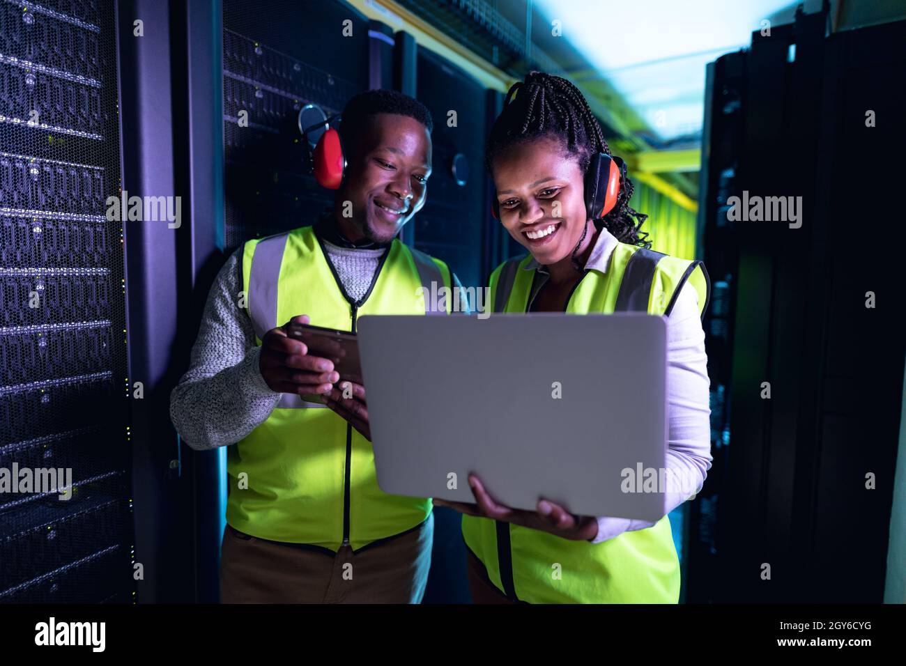 Happy african american computer technicians wearing headphones using ...