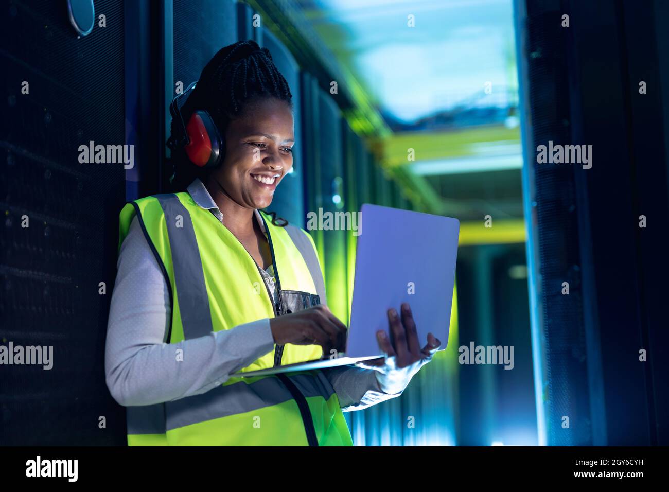 African american female computer technician wearing headphones using ...