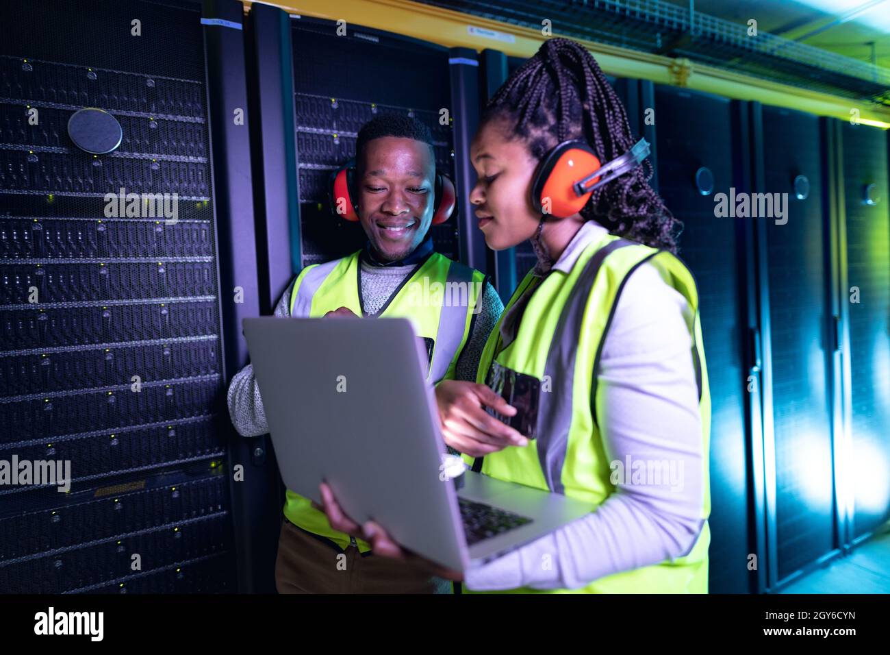 African american computer technicians wearing headphones using laptop ...