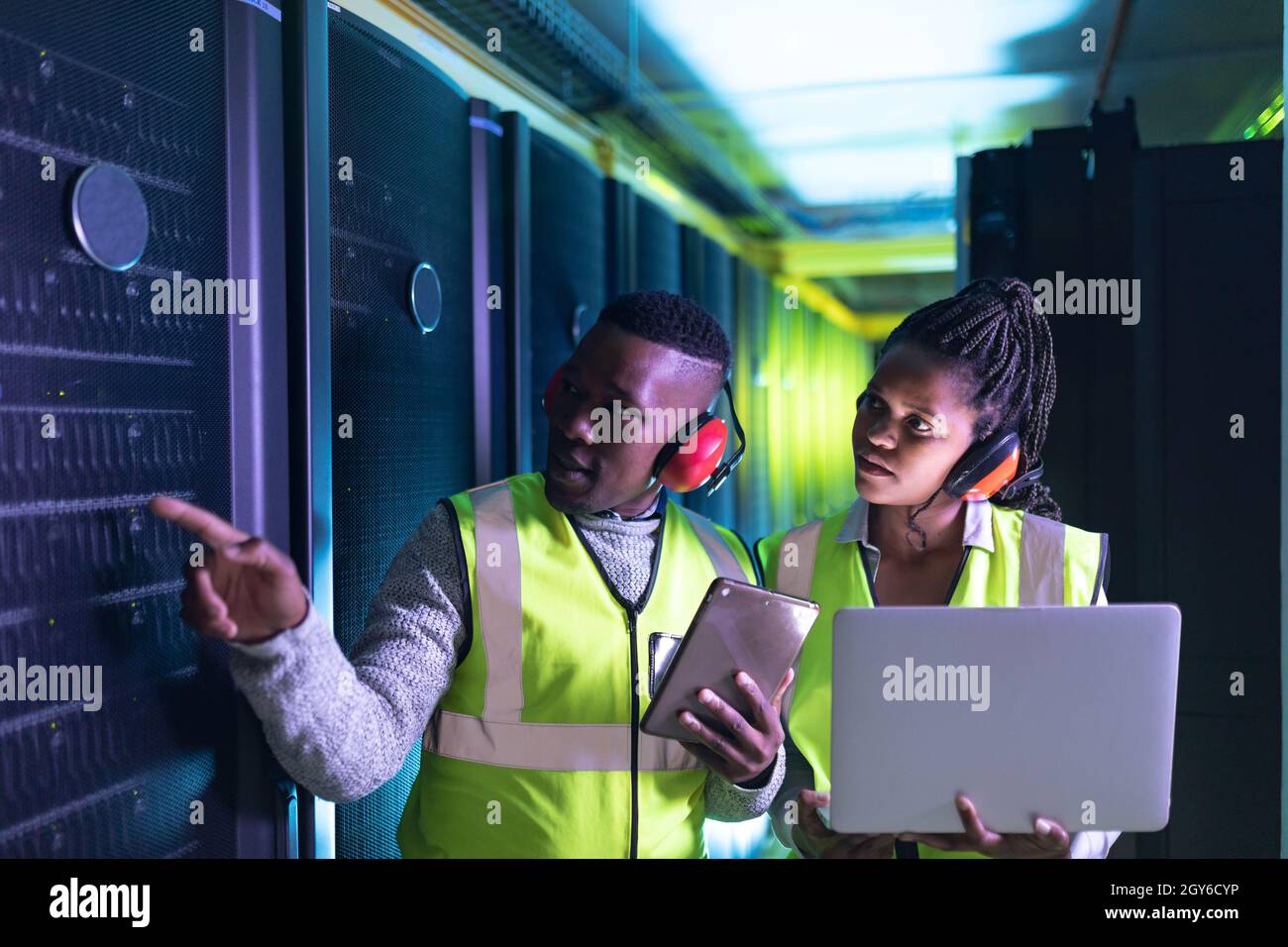 African american computer technicians wearing headphones using laptop ...