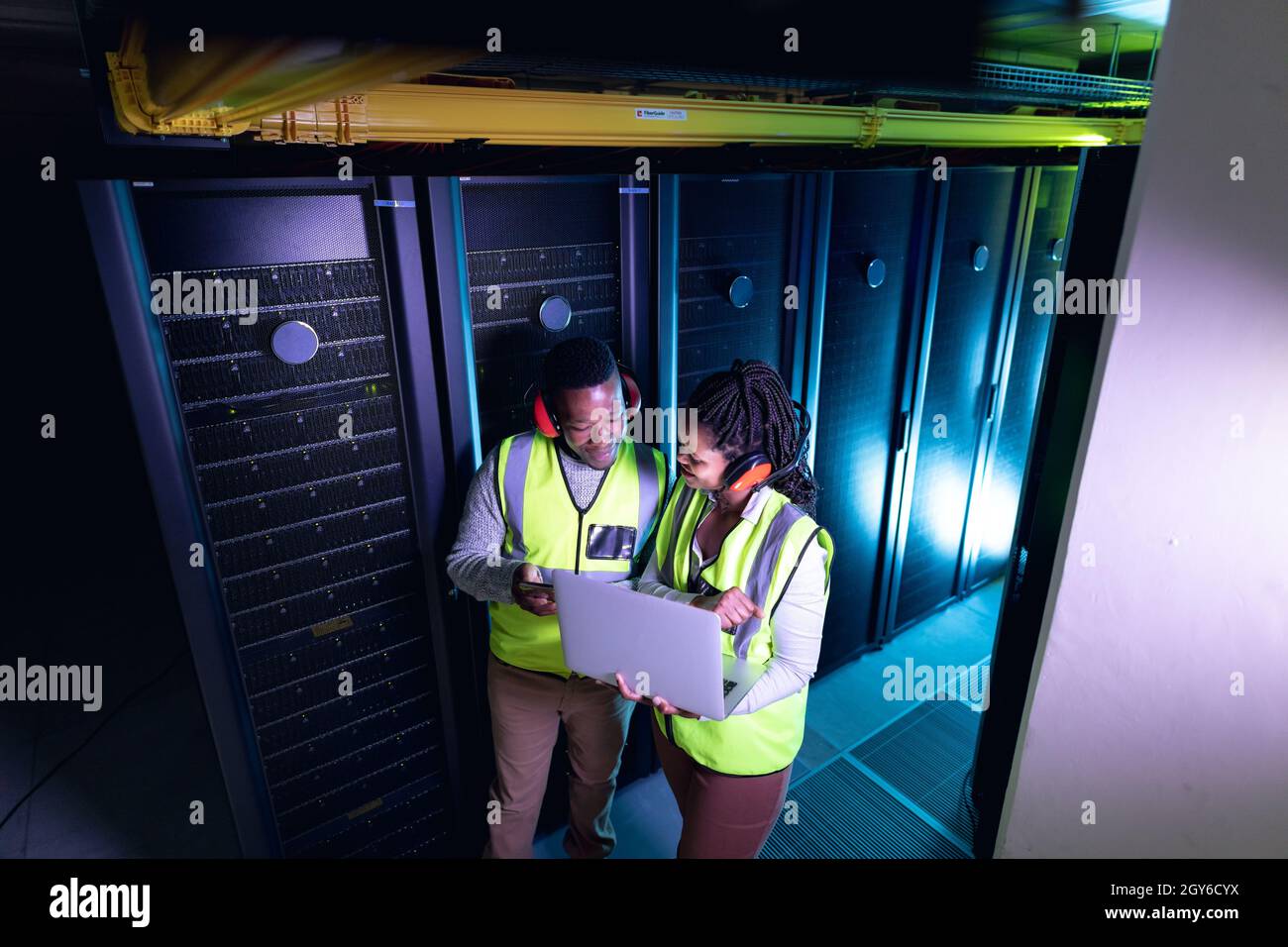 African american computer technicians wearing headphones using laptop ...