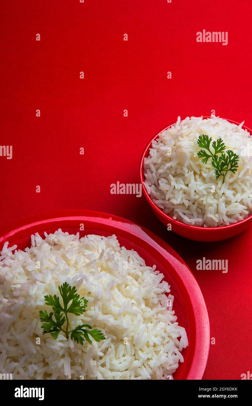 Cooked plain white basmati rice in bowl and plate on red background ...