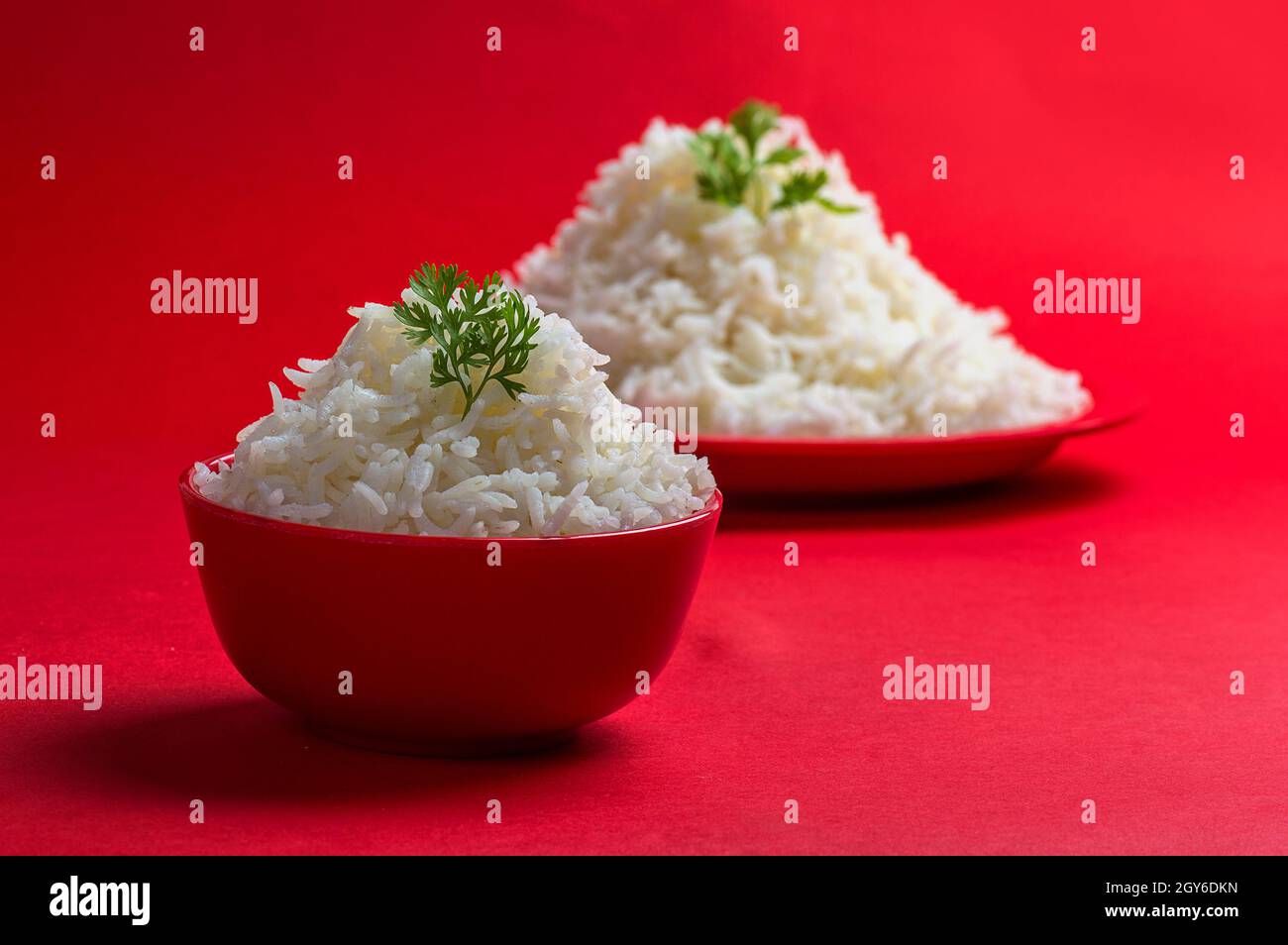Cooked plain white basmati rice in bowl and plate on red background ...