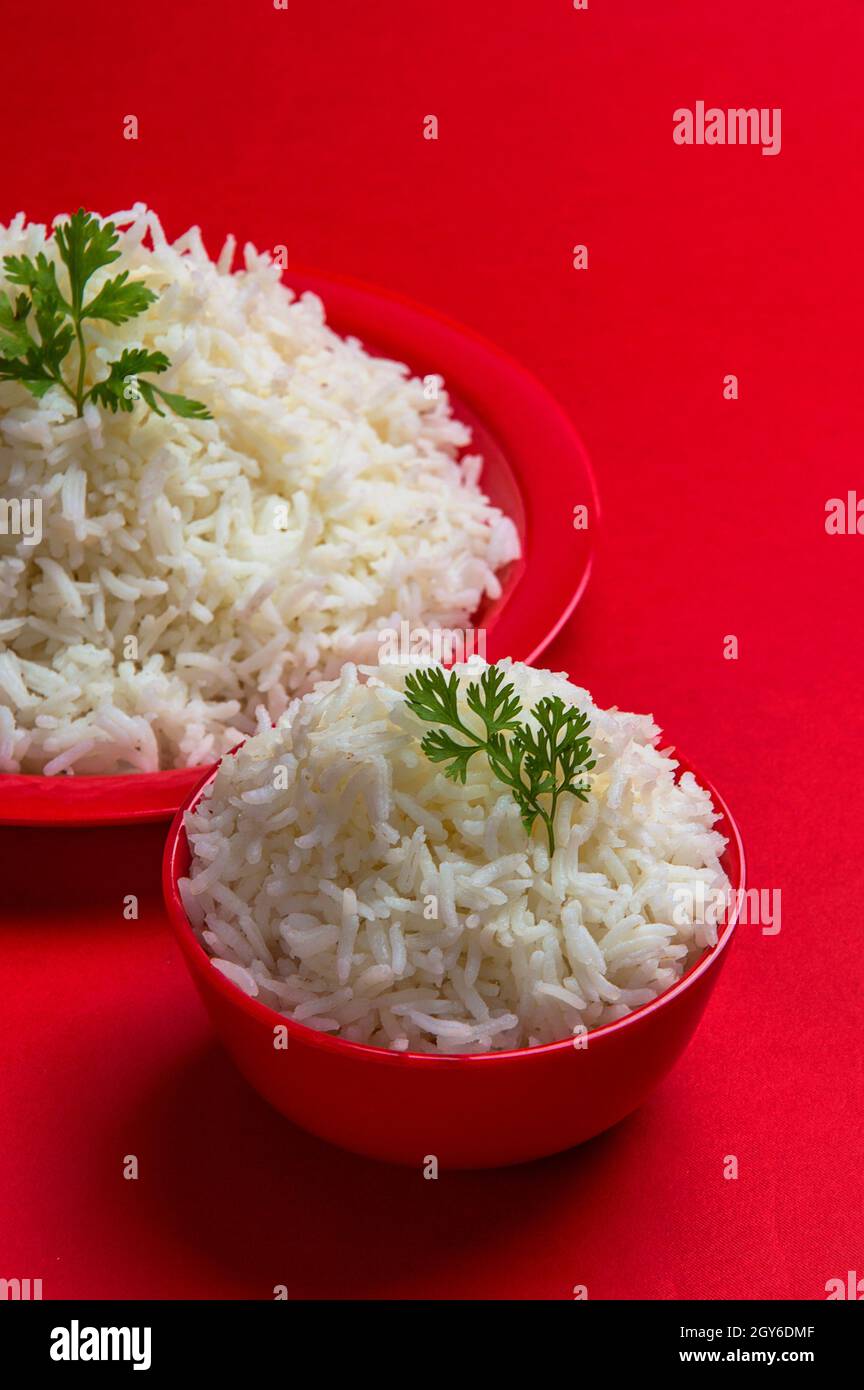 Cooked plain white basmati rice in bowl and plate on red background ...