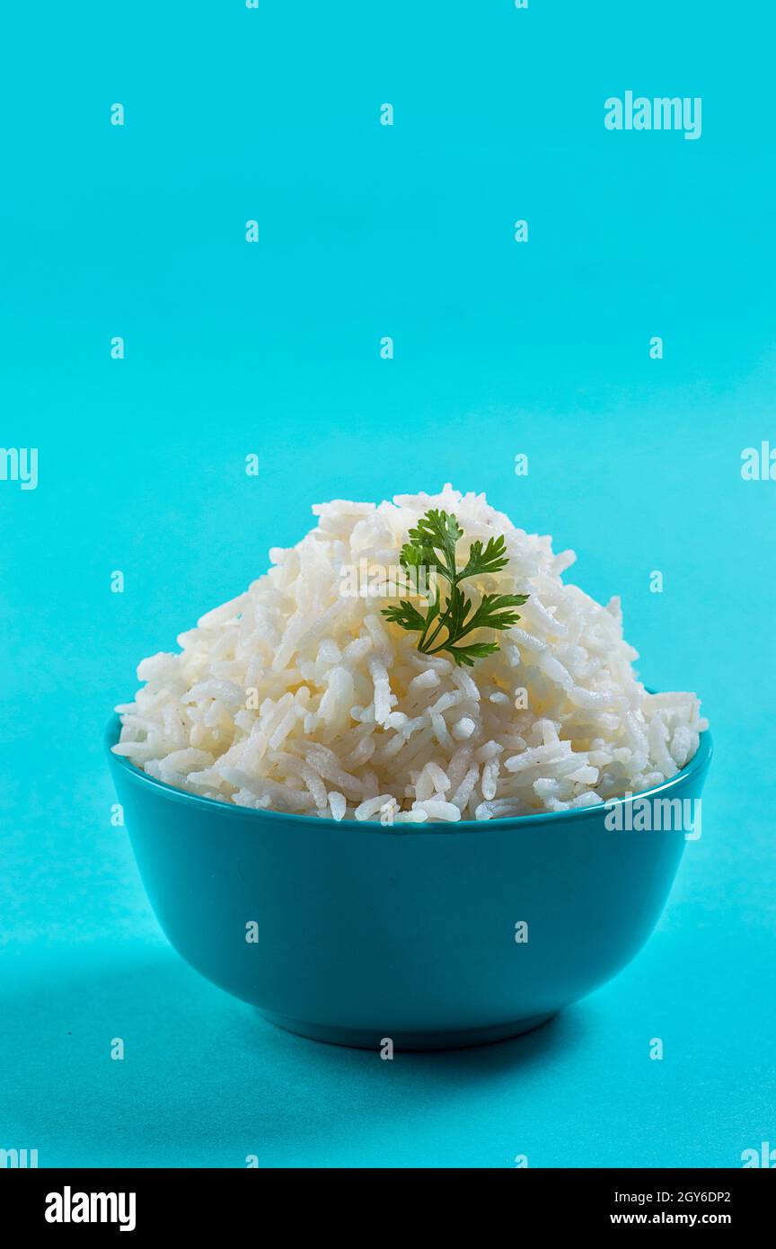 Cooked plain white basmati rice with corriander in a blue bowl on blue ...