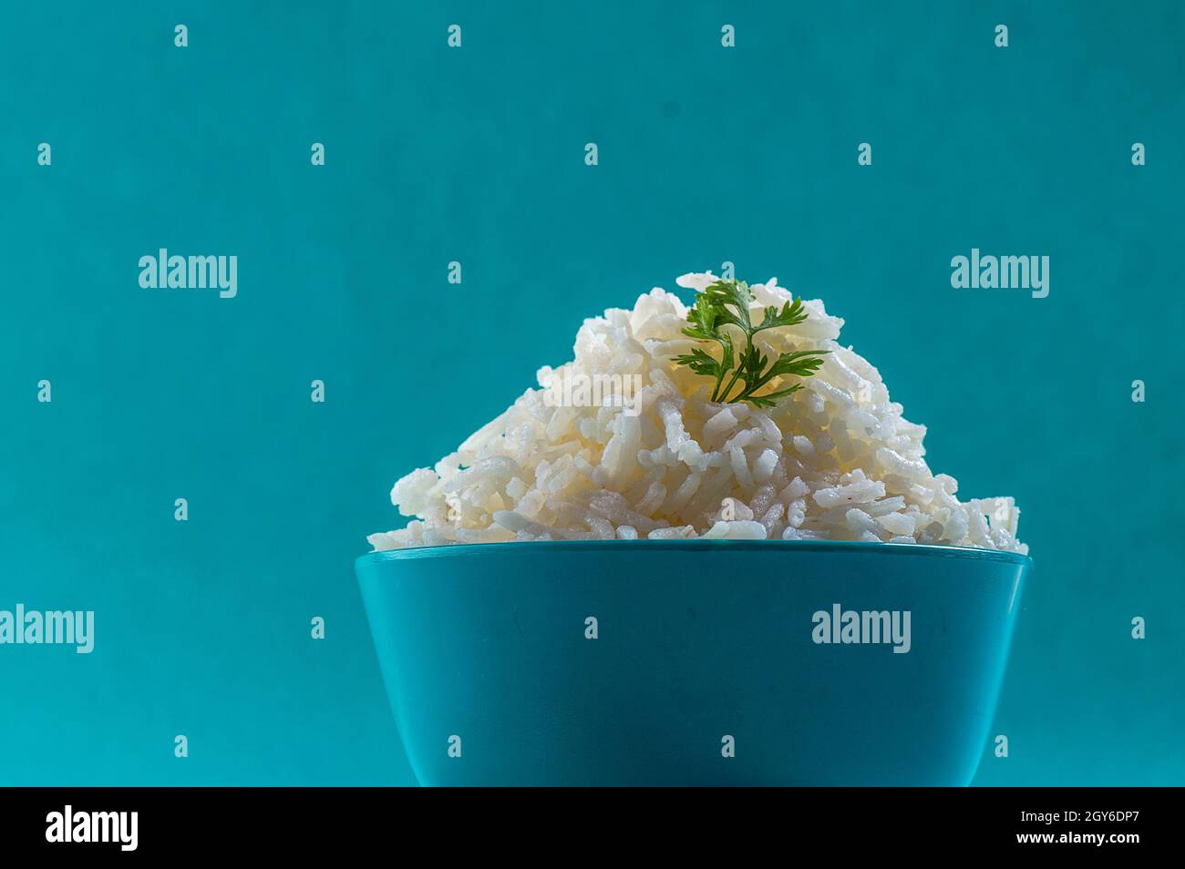 Cooked plain white basmati rice with corriander in a blue bowl on blue ...