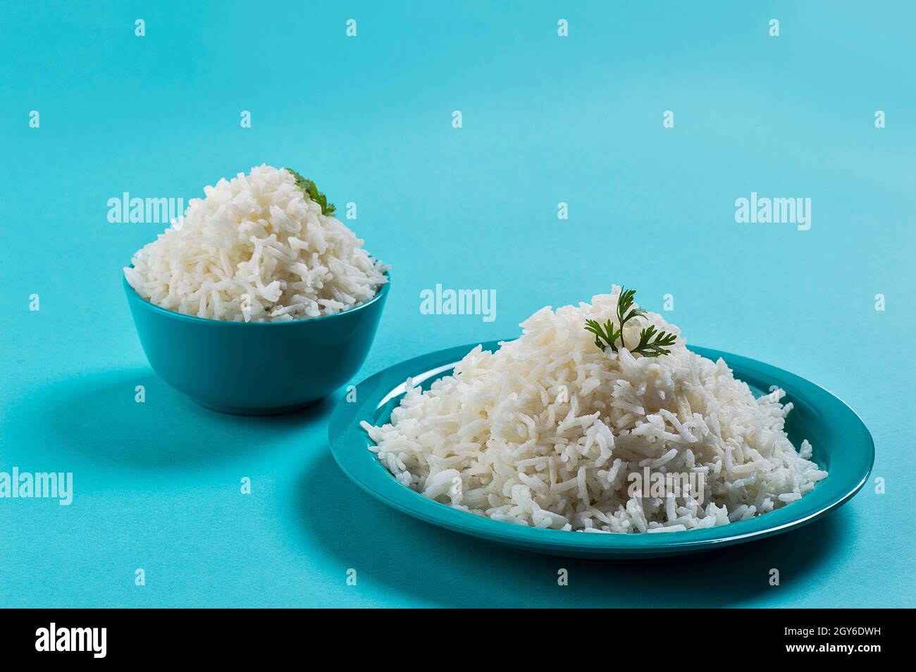 Cooked plain white basmati rice in a blue plate and bowl on blue ...
