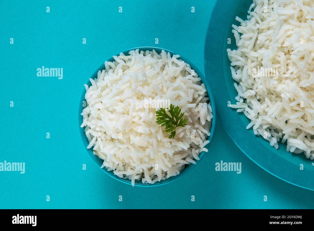 Cooked plain white basmati rice in a blue plate and bowl on blue ...