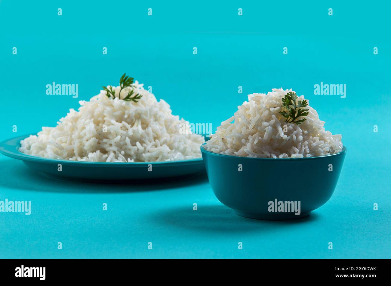 Cooked plain white basmati rice in a blue plate and bowl on blue ...