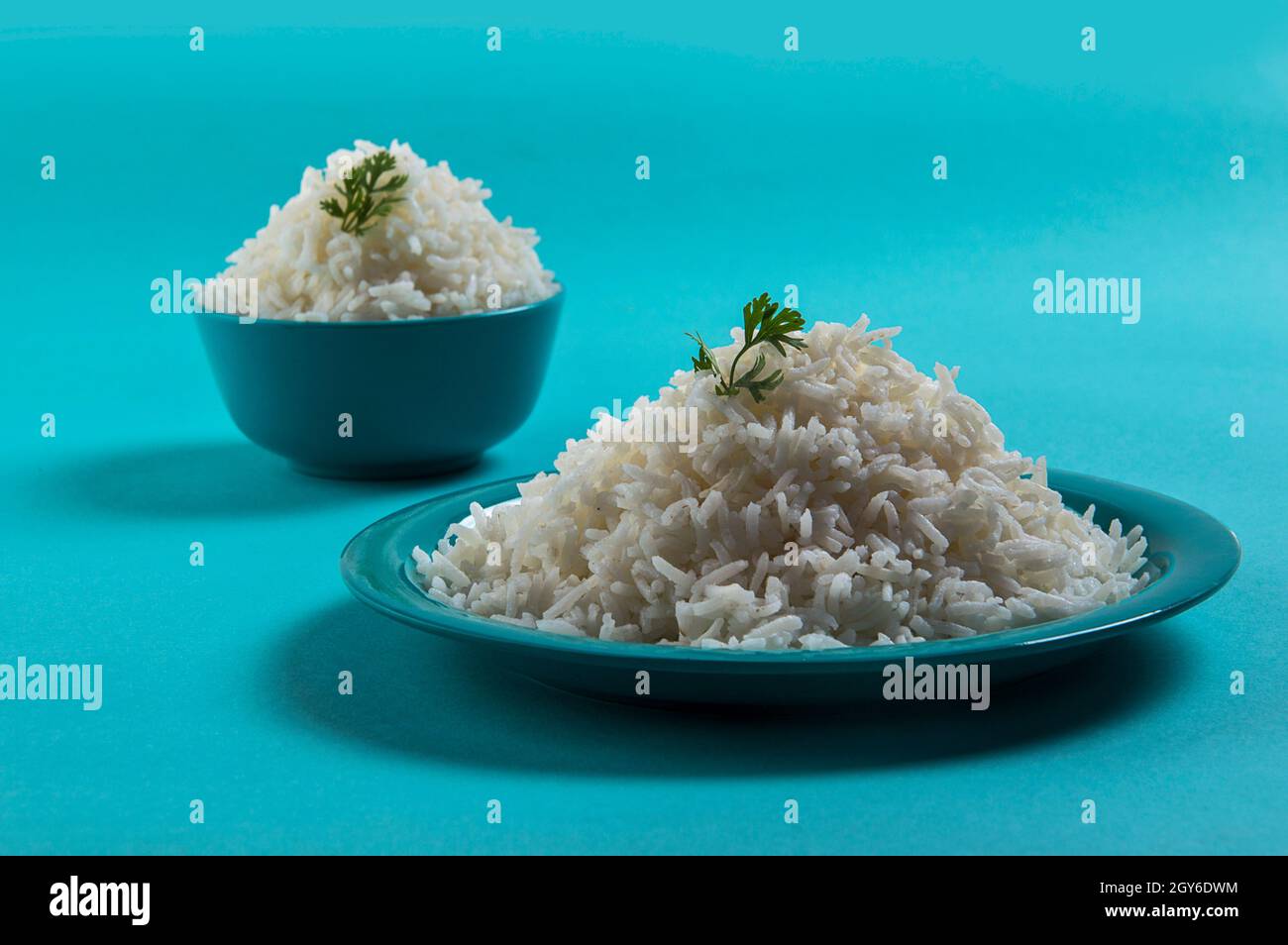 Cooked plain white basmati rice in a blue plate and bowl on blue ...