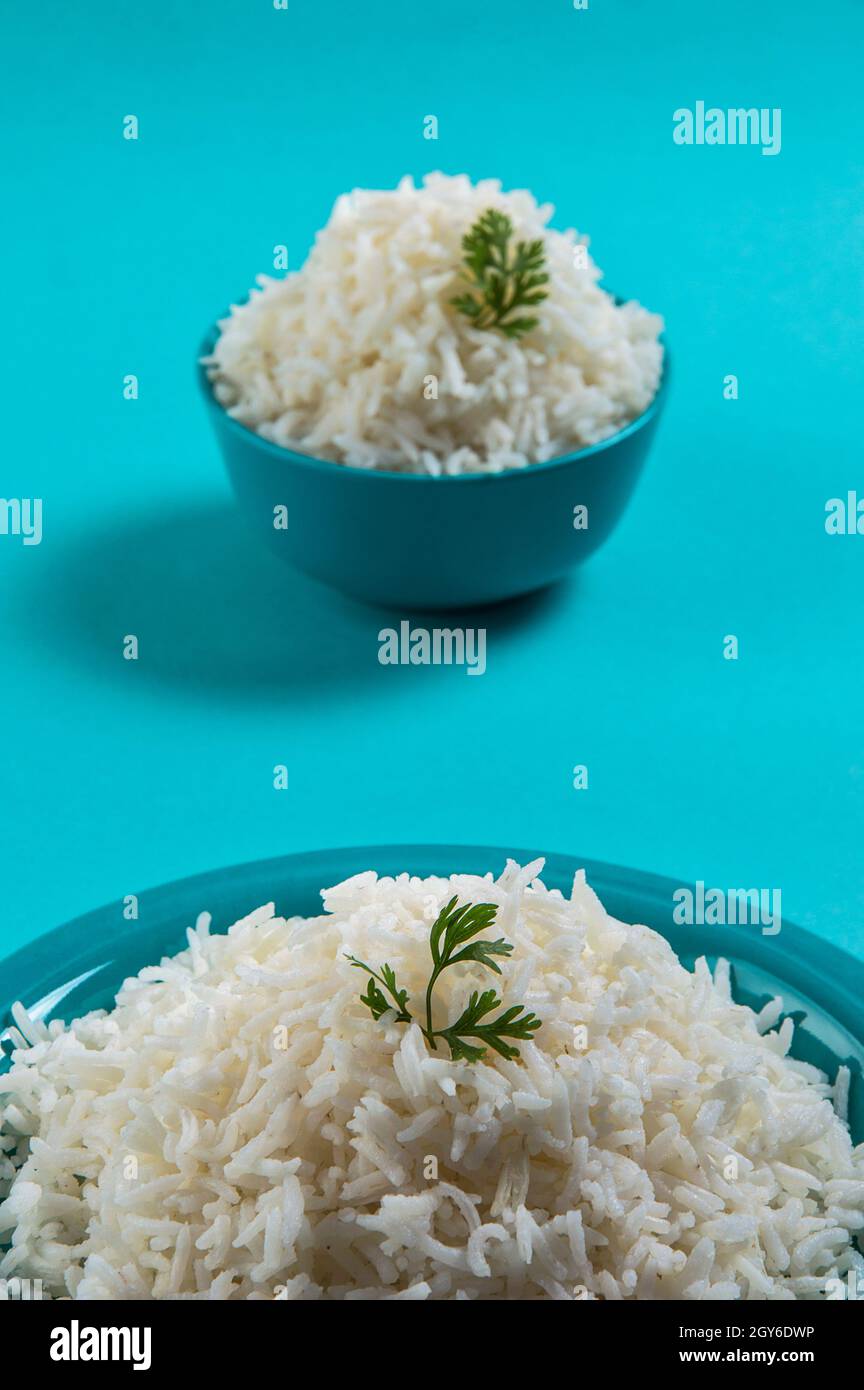 Cooked plain white basmati rice in a blue plate and bowl on blue ...
