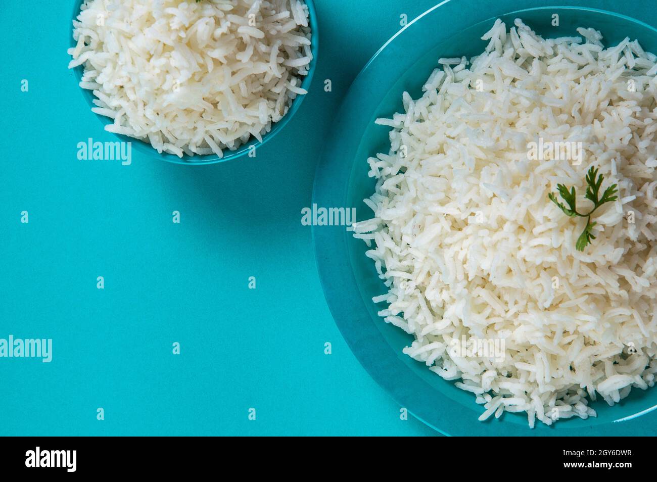 Cooked plain white basmati rice in a blue plate and bowl on blue ...