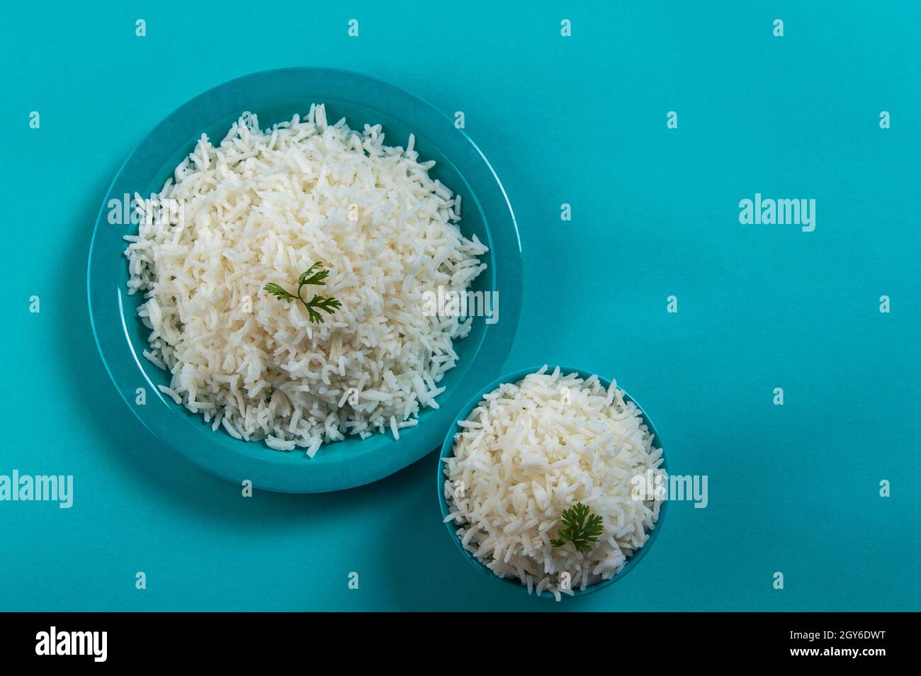 Cooked plain white basmati rice in a blue plate and bowl on blue ...