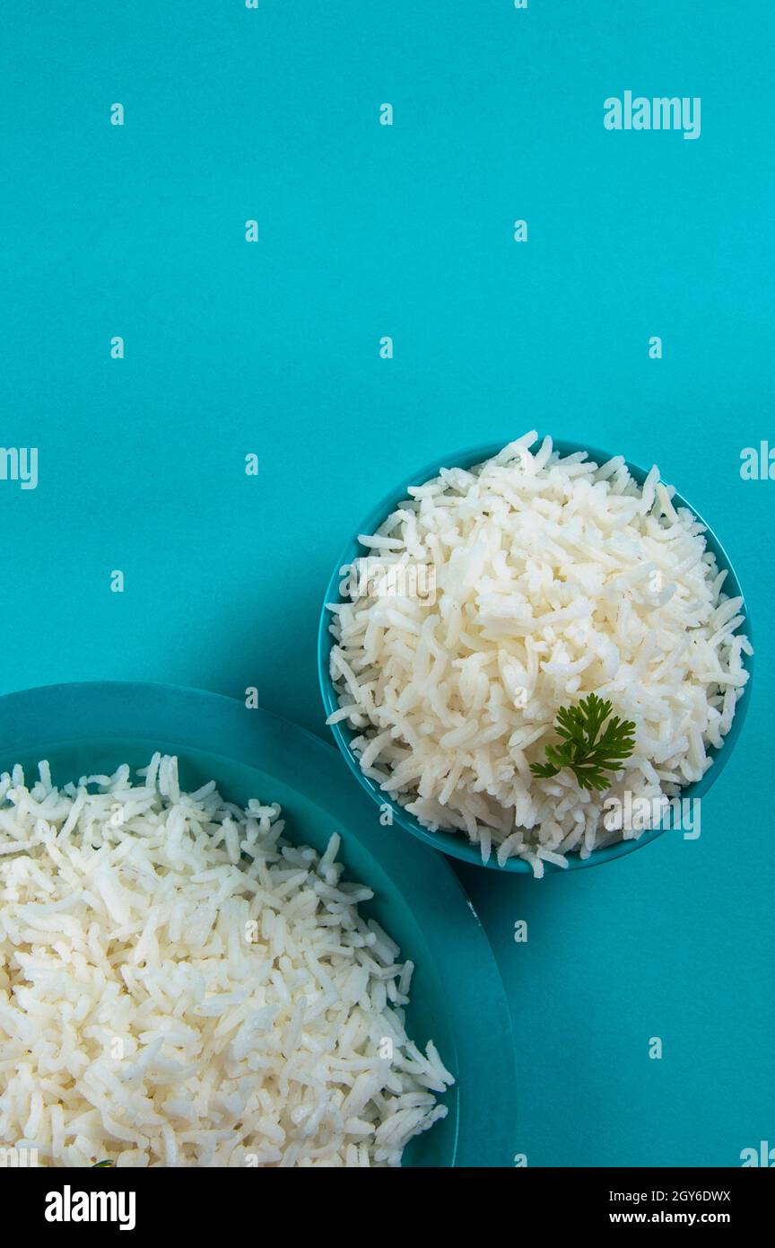 Cooked plain white basmati rice in a blue plate and bowl on blue ...