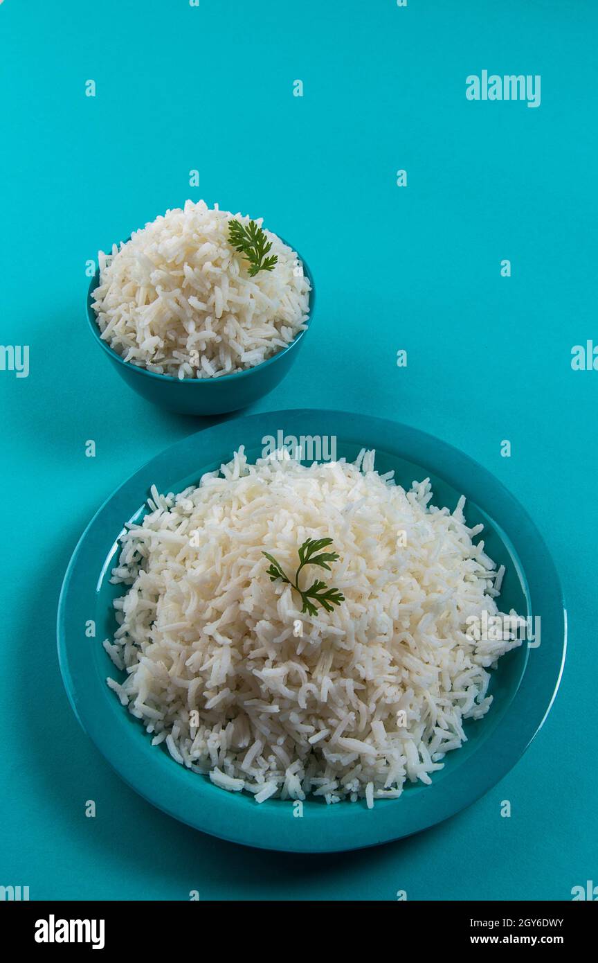 Cooked plain white basmati rice in a blue plate and bowl on blue ...