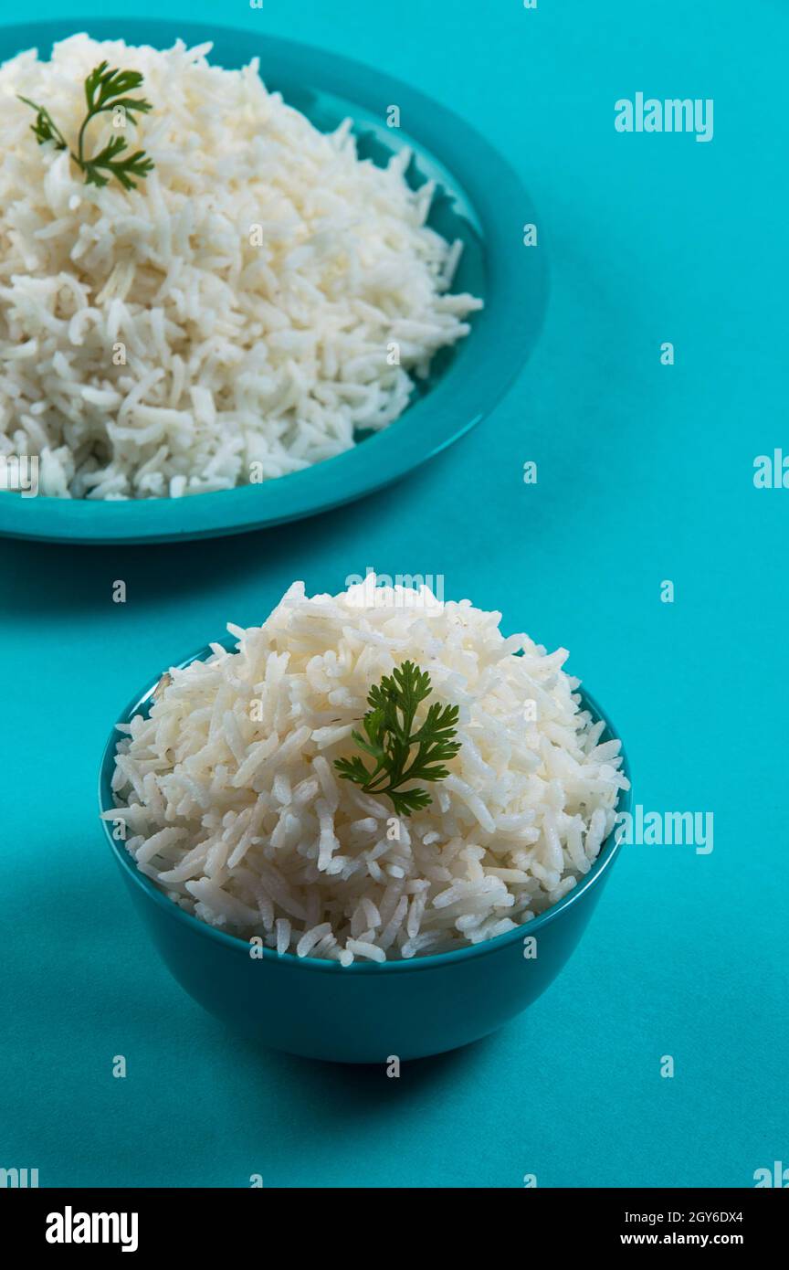 Cooked plain white basmati rice in a blue plate and bowl on blue ...
