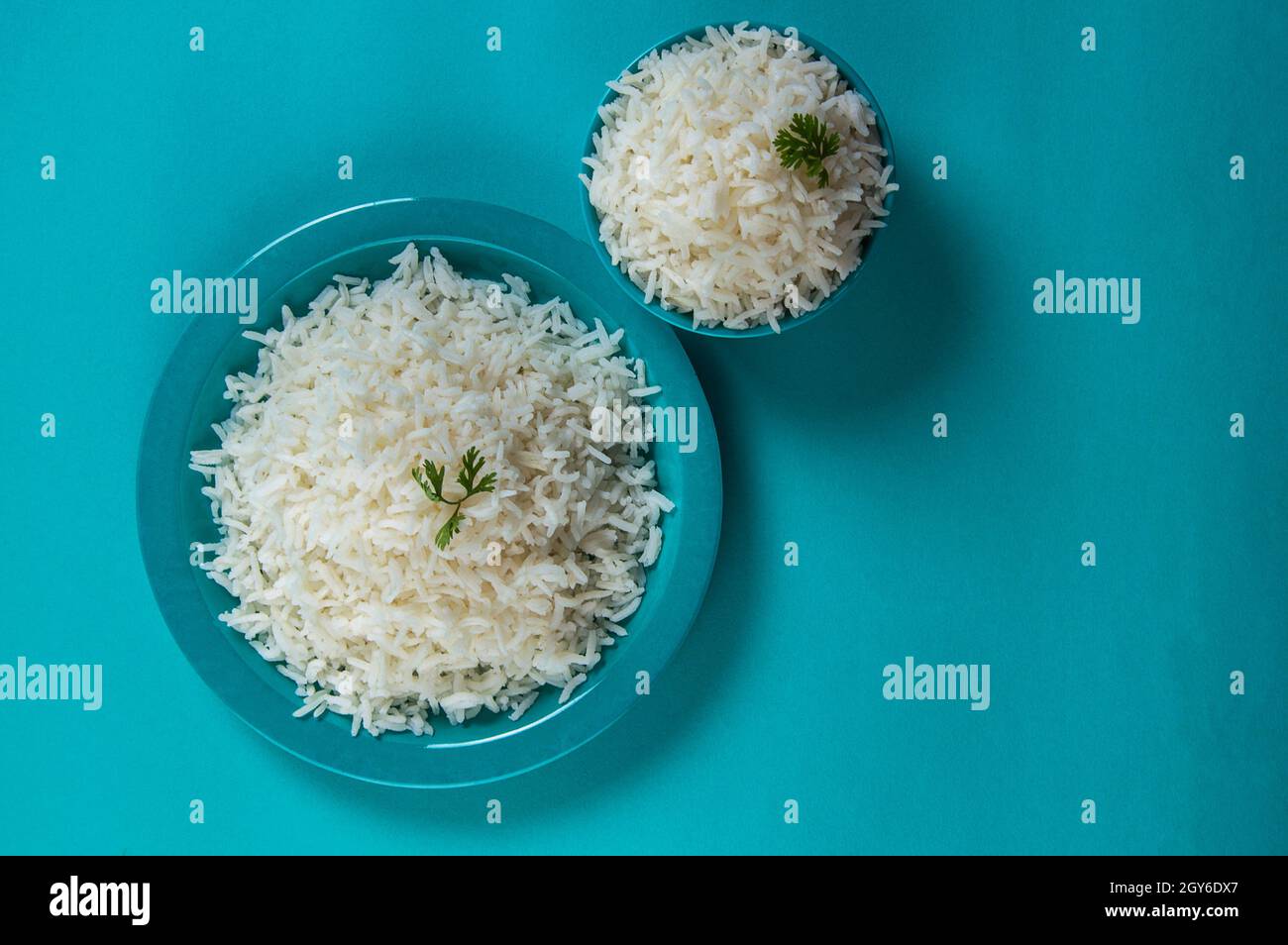 Cooked plain white basmati rice in a blue plate and bowl on blue ...