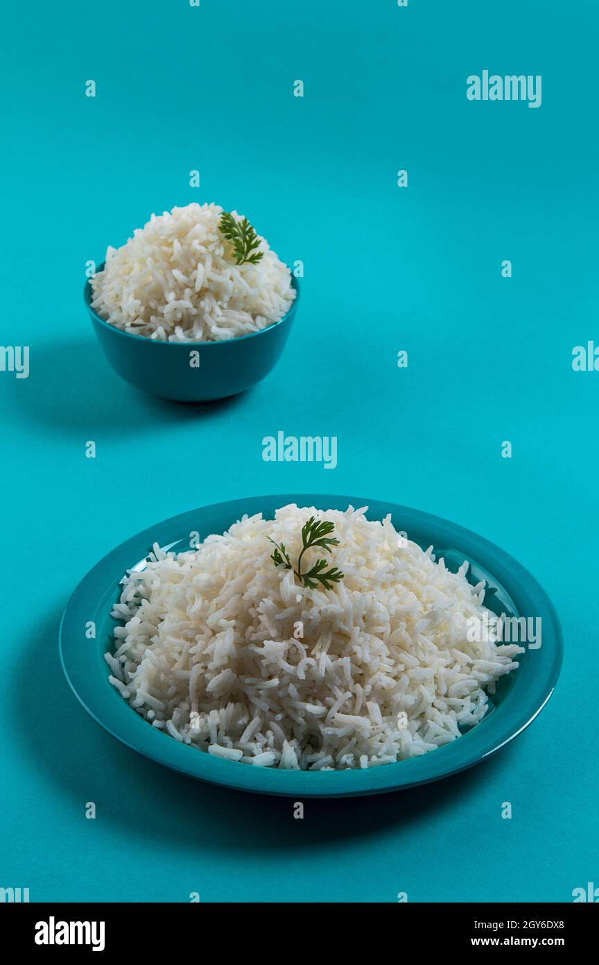 Cooked plain white basmati rice in a blue plate and bowl on blue ...