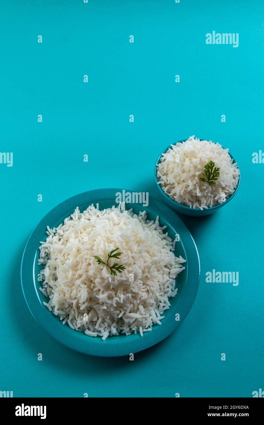 Cooked plain white basmati rice in a blue plate and bowl on blue ...