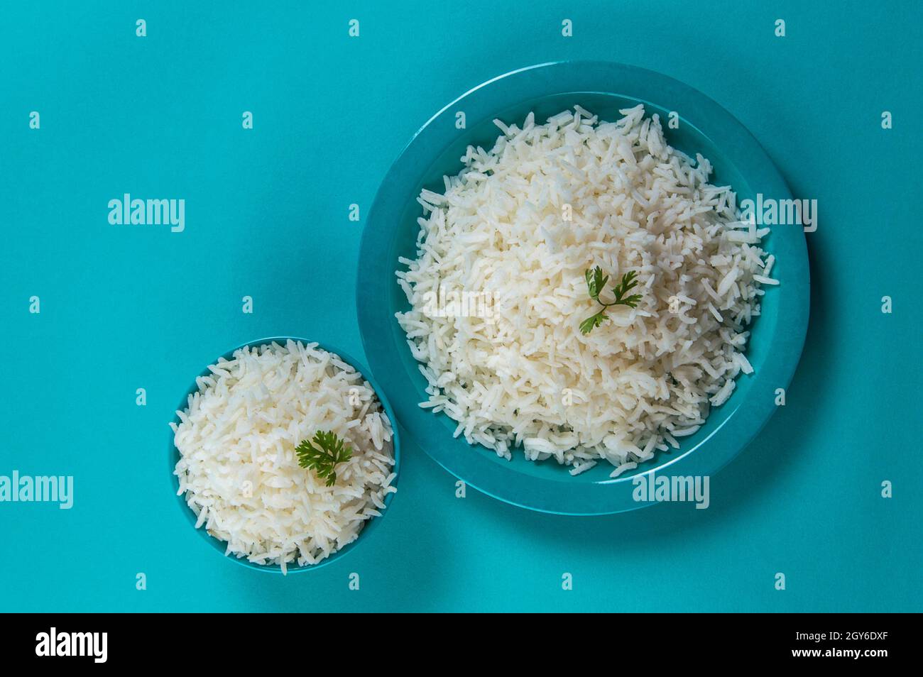 Cooked plain white basmati rice in a blue plate and bowl on blue ...