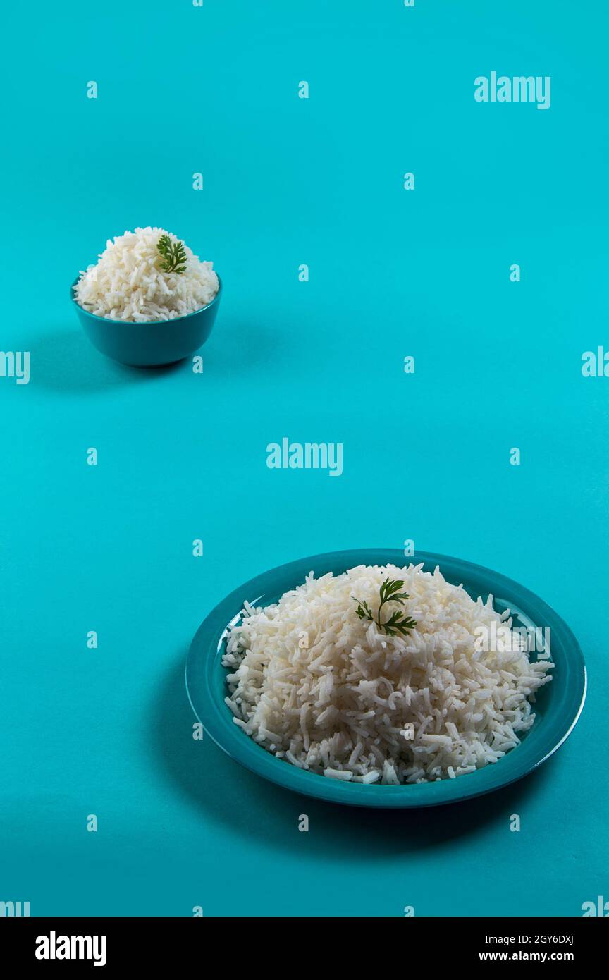 Cooked plain white basmati rice in a blue plate and bowl on blue ...