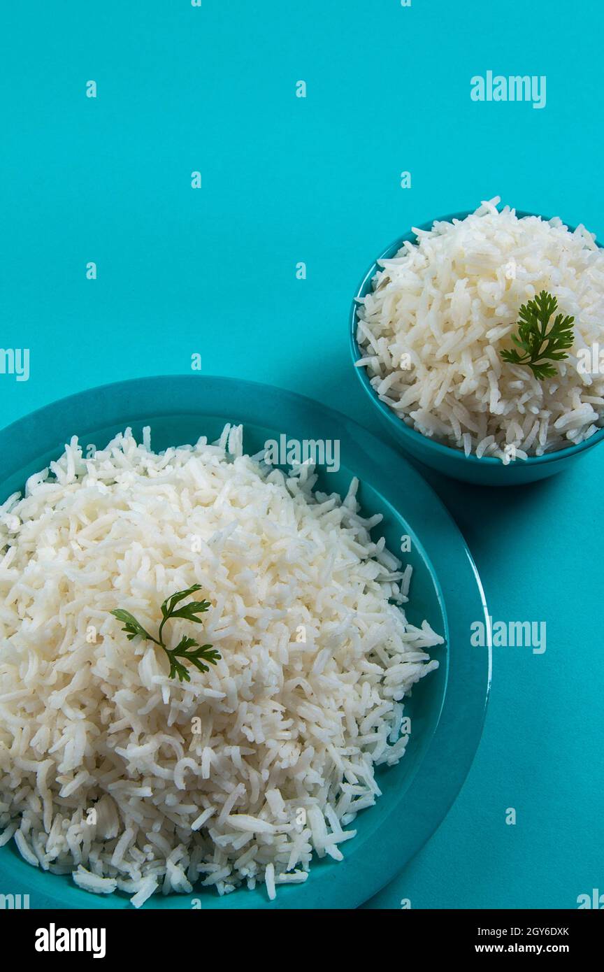 Cooked plain white basmati rice in a blue plate and bowl on blue ...
