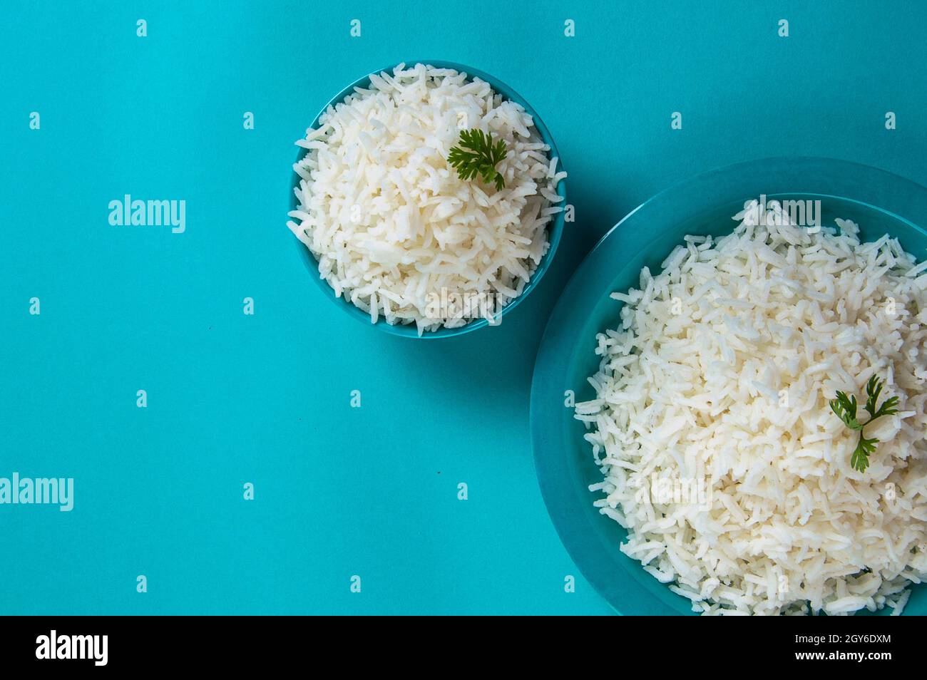 Cooked plain white basmati rice in a blue plate and bowl on blue ...