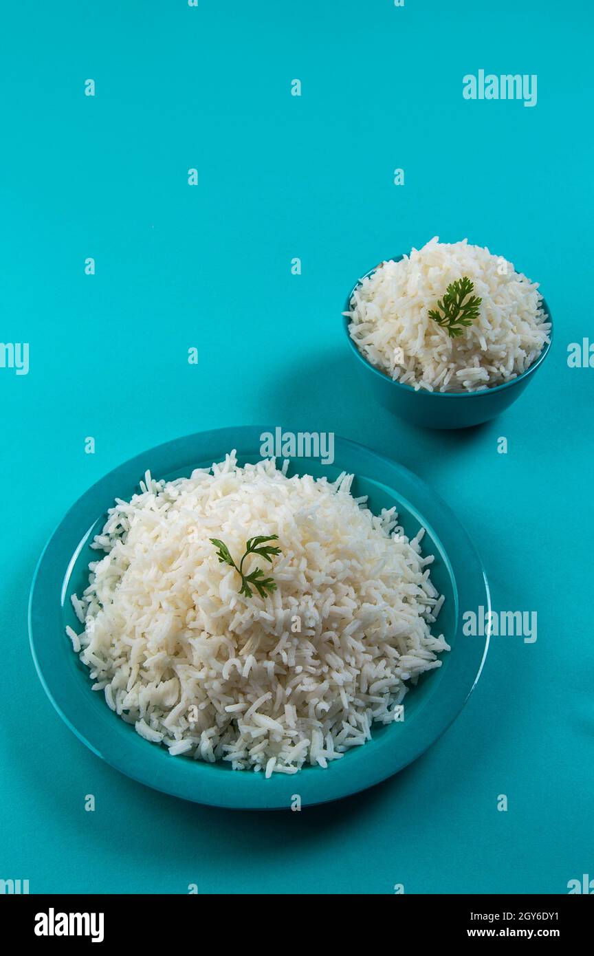 Cooked plain white basmati rice in a blue plate and bowl on blue ...