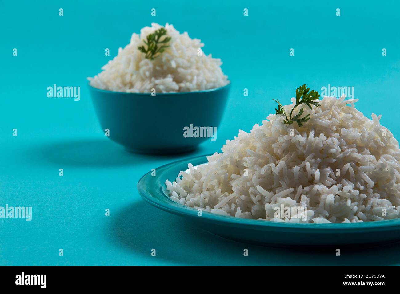 Cooked plain white basmati rice in a blue plate and bowl on blue ...
