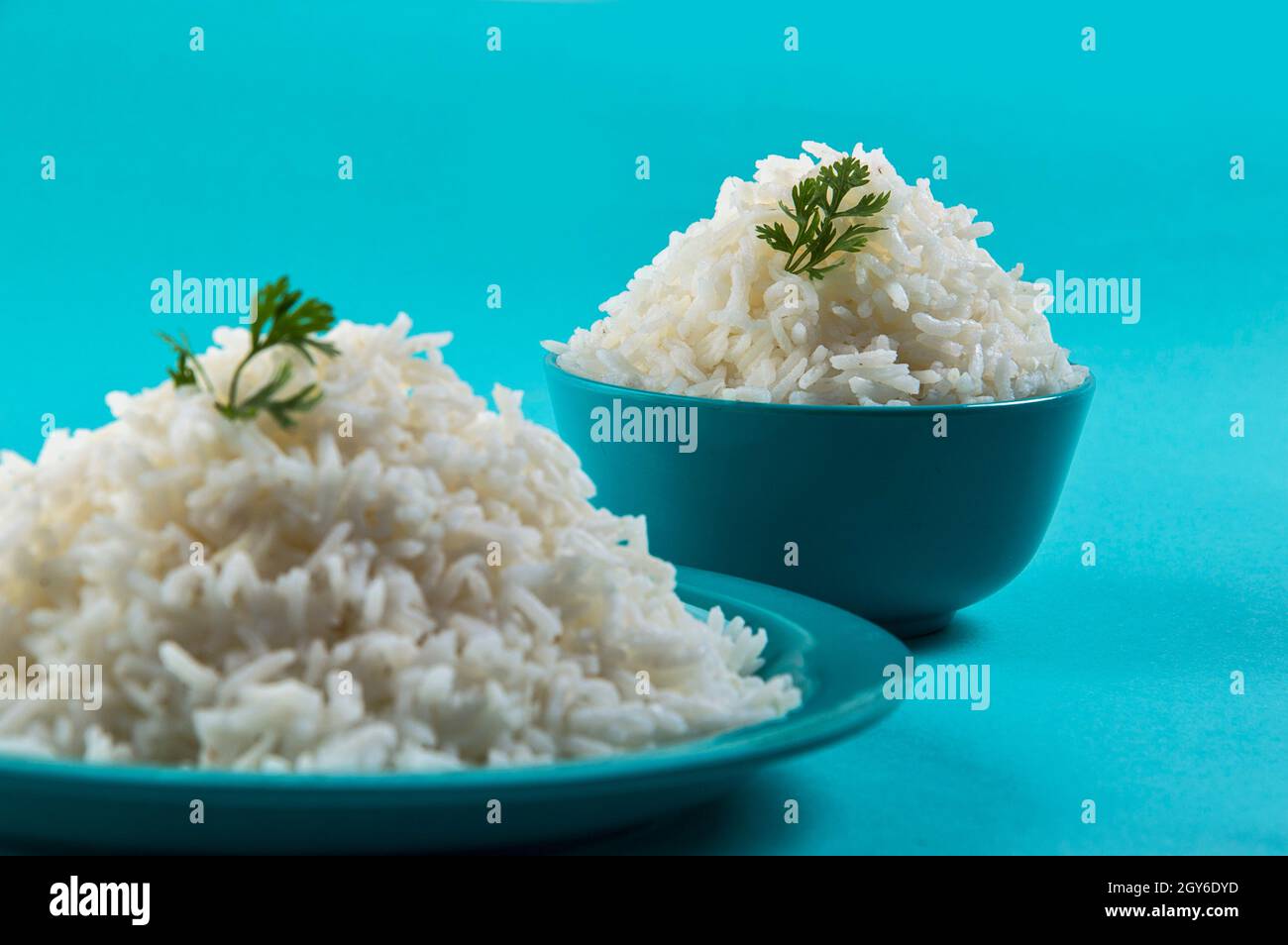 Cooked plain white basmati rice in a blue plate and bowl on blue ...