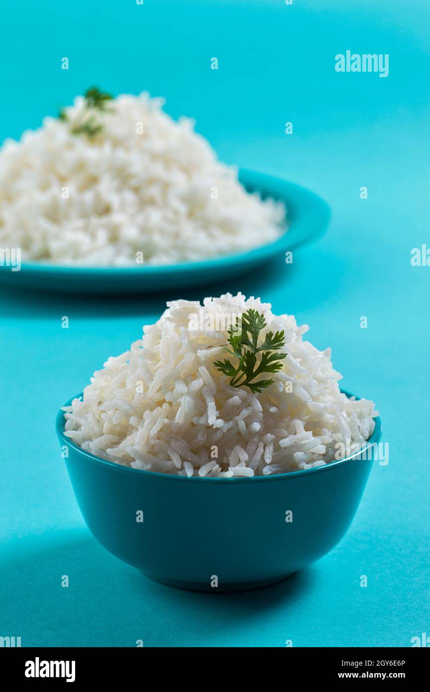 Cooked plain white basmati rice in a blue plate and bowl on blue ...
