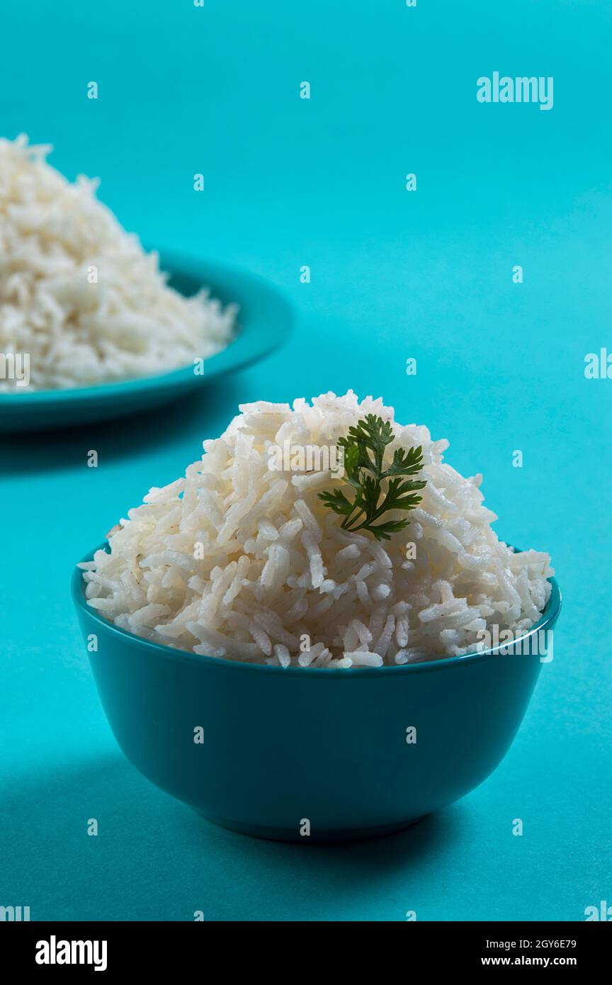 Cooked plain white basmati rice in a blue plate and bowl on blue ...