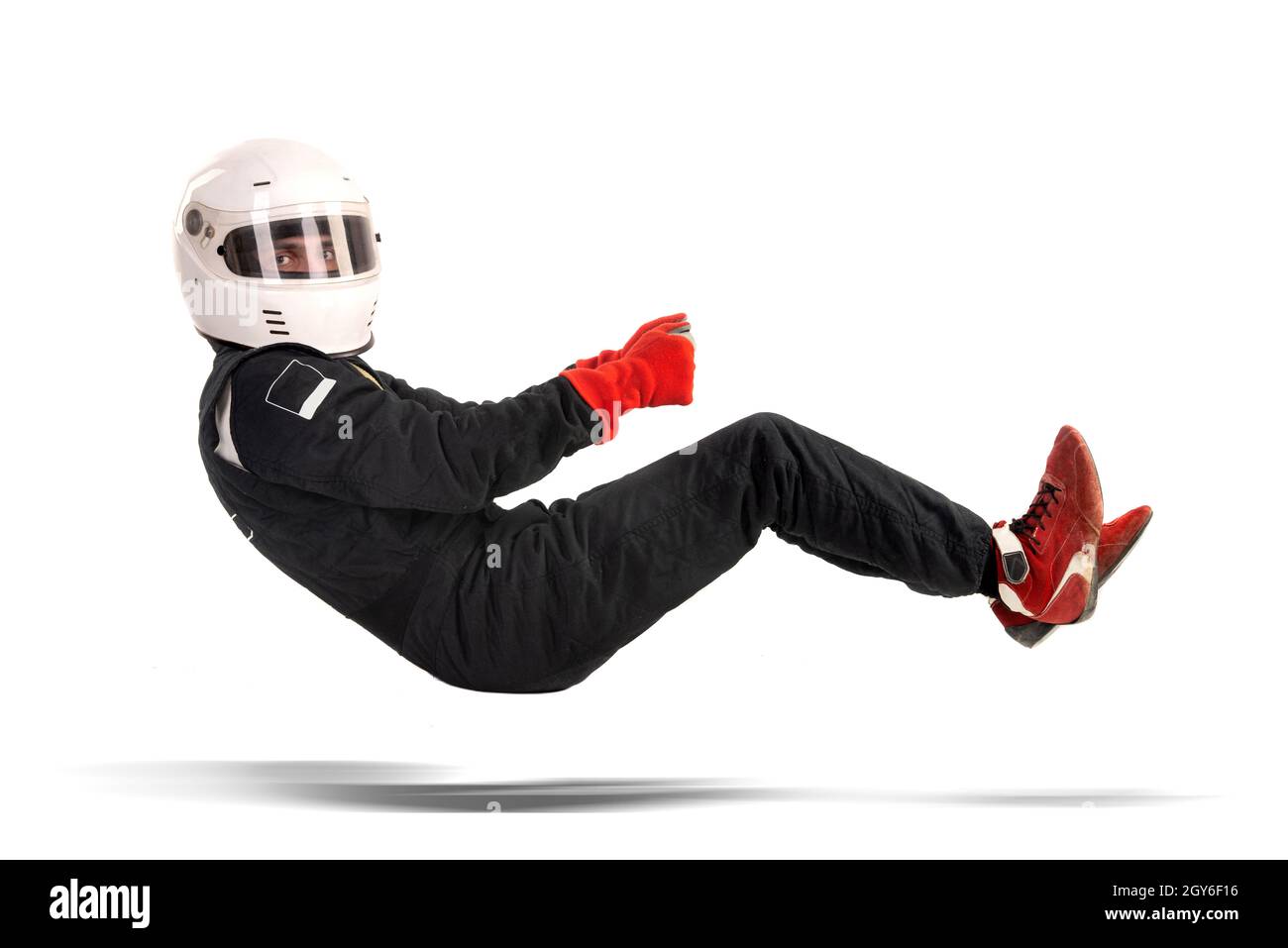 Racing driver in racing position with complete gear isolated in white ...