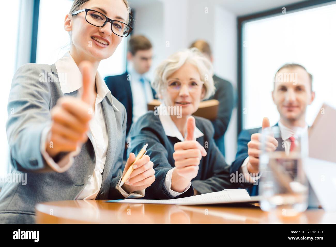 Business people showing thumbs up upon successful completion of project ...