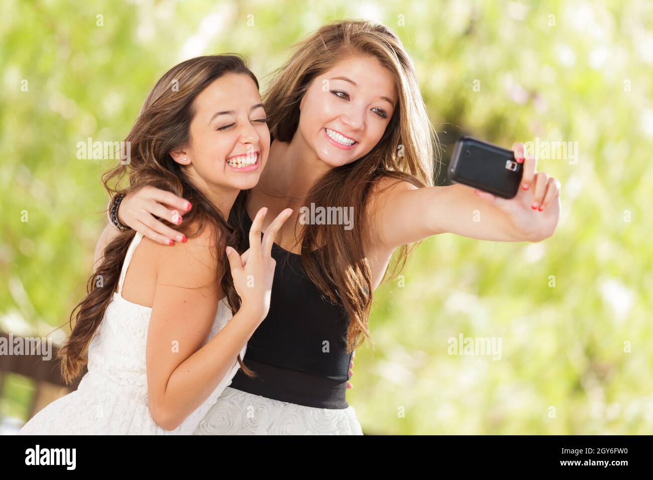 Two Attractive Mixed Race Girlfriends Using Their Smart Cell Phones For