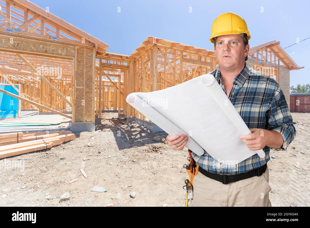 Male Contractor With House Plans Wearing Hard Hat In Front of New House ...
